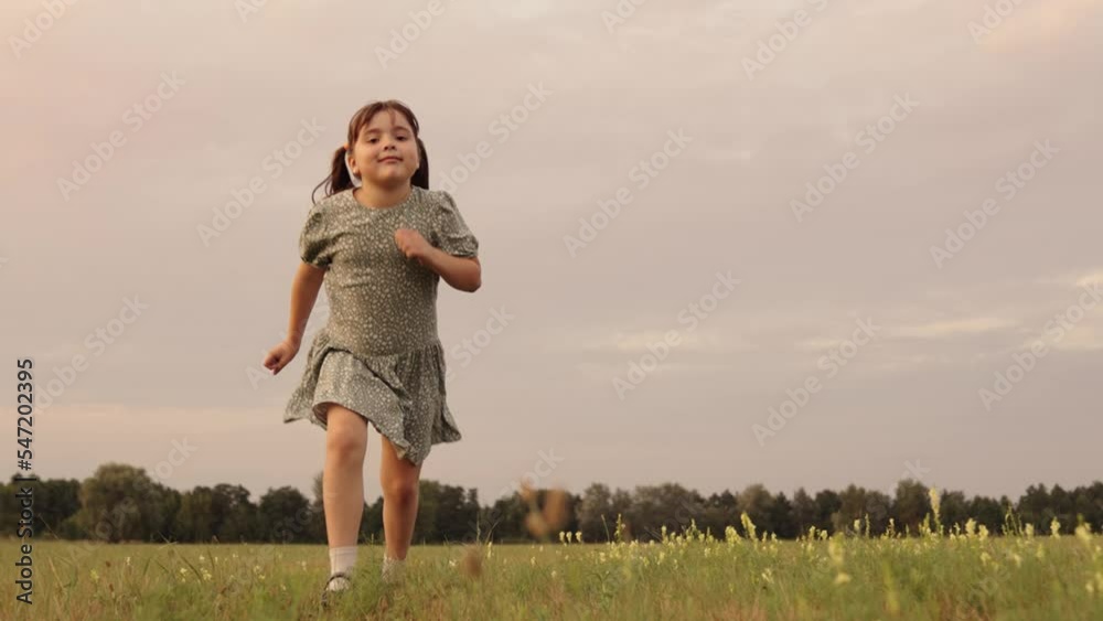 happy little girl runs across green field. cheerful child kid run ...