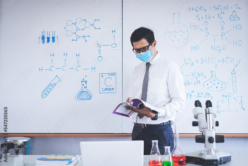Science teacher wearing mask stands teach science class in the ...