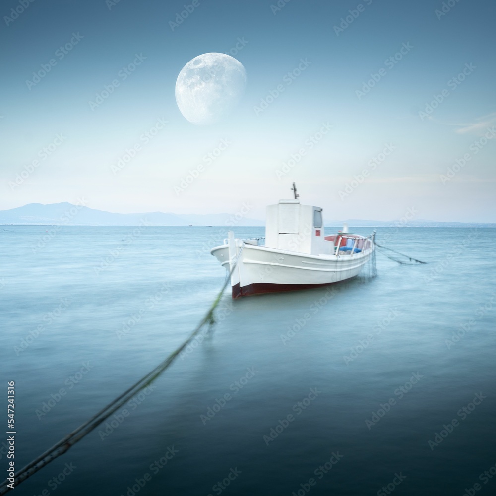 Beautiful scene of a boat with a rope to the beach under moon in the ...