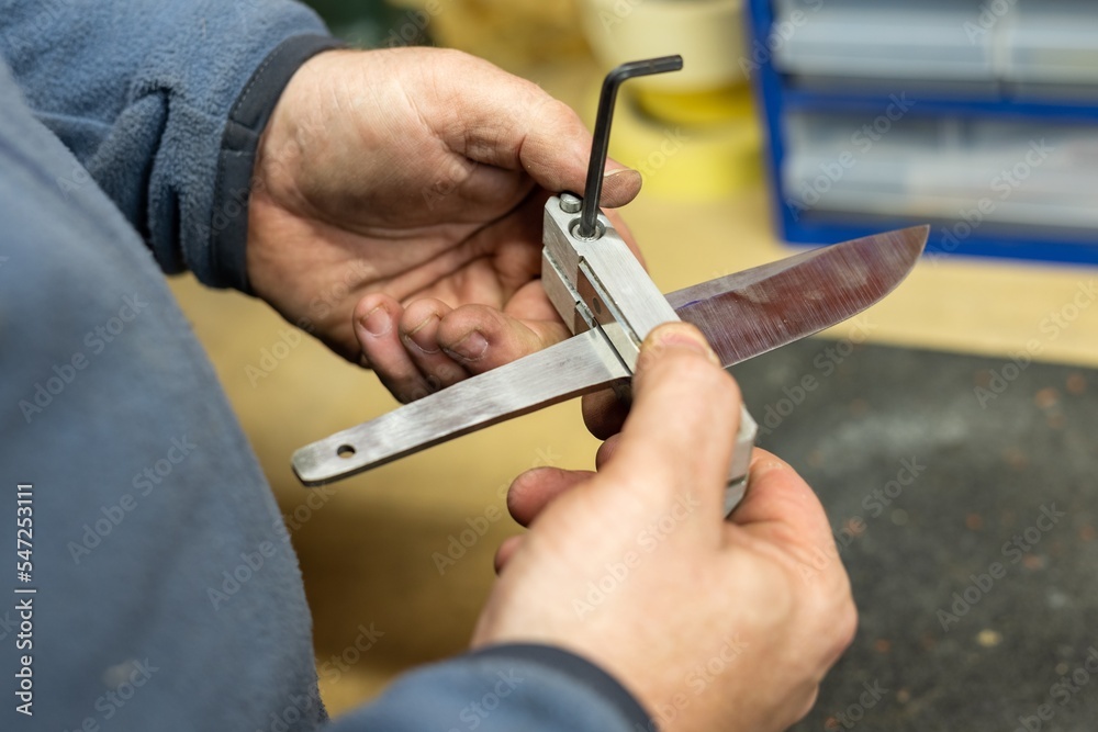 The knife maker shapes and sharpens the newly constructed blade ...