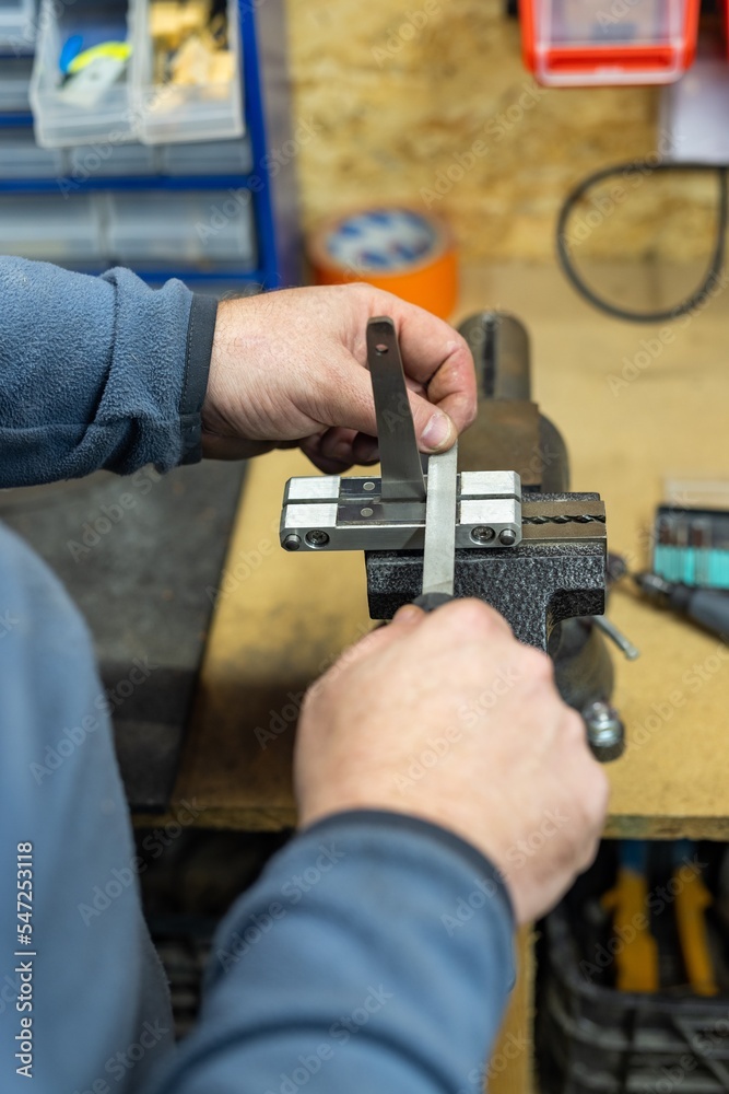 The knife maker shapes and sharpens the newly constructed blade ...