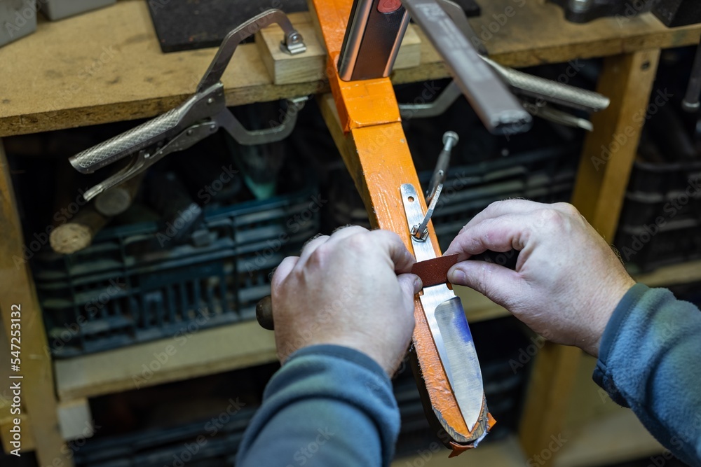The knife maker shapes and sharpens the newly constructed blade ...
