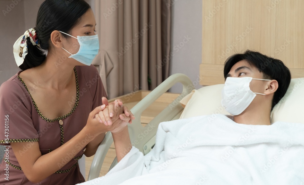 Young patient with attentive visitor and family holding hands in ...
