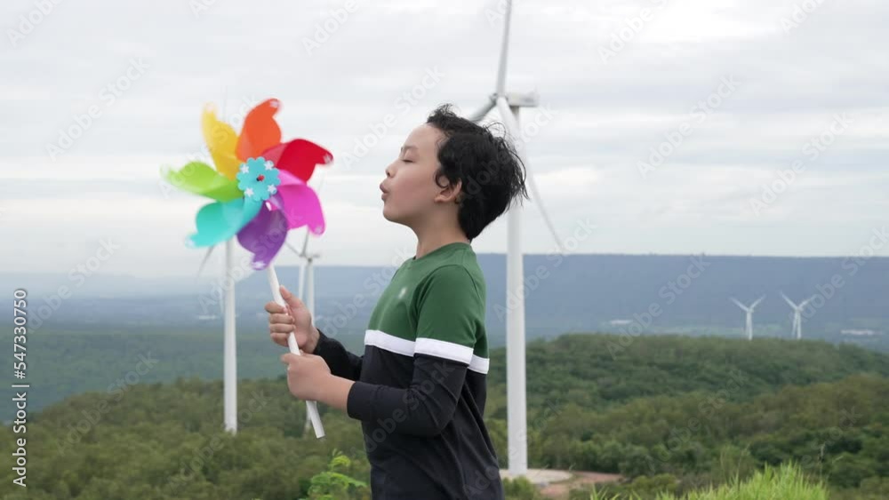 Progressive young asian boy playing with wind turbine toy in the wind ...