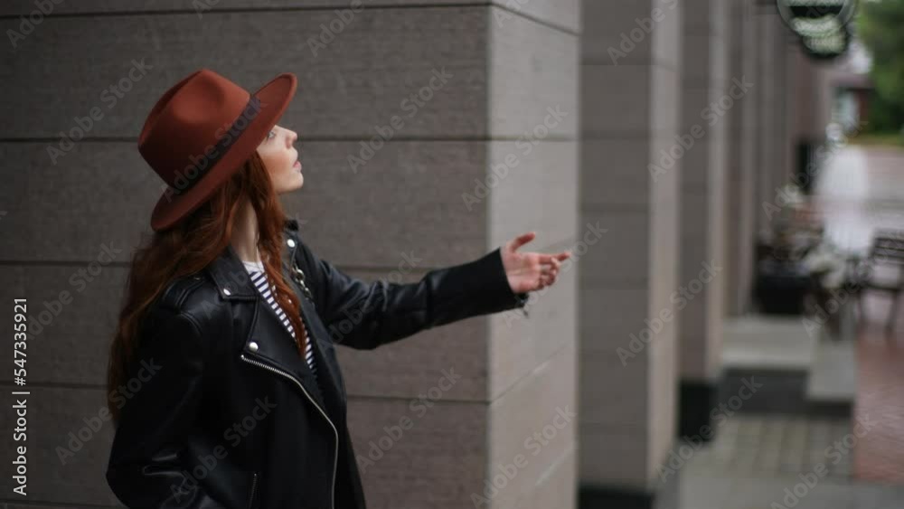 Attractive young woman in stylish hat coming out of entrance of ...