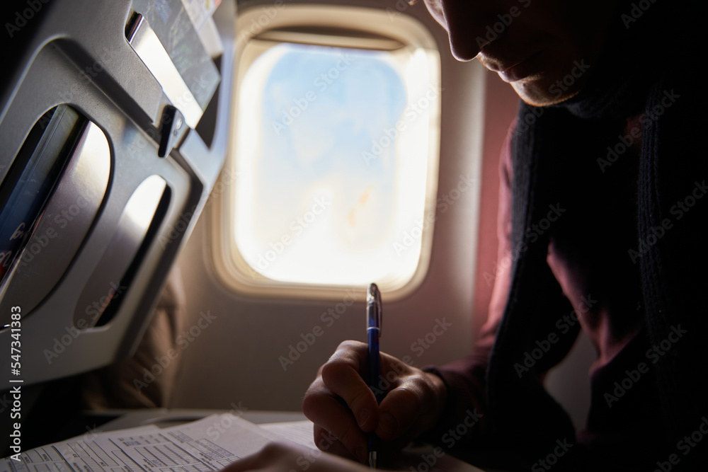 Tourist hand filling immigration form on flight to visit destination ...