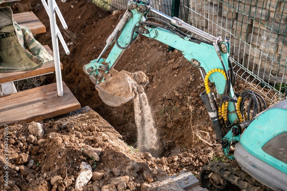 Foto de Mini excavator digs a trench to lay pipes. Close up of an ...