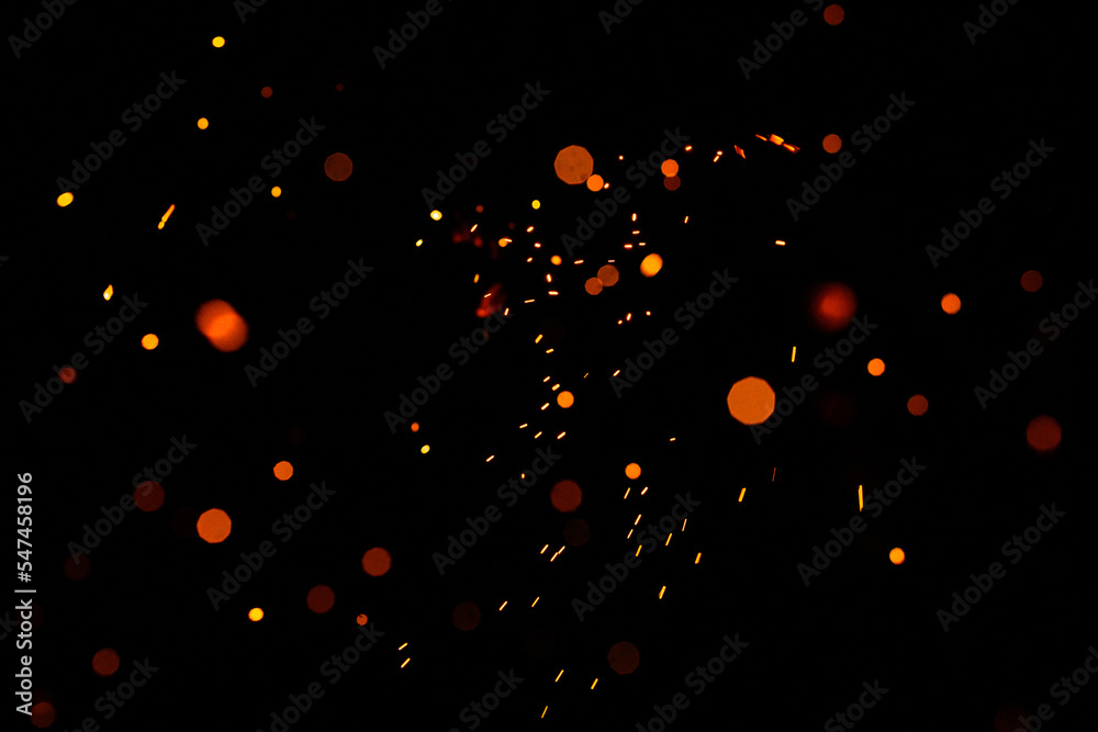 Particles of burning embers fly and glow isolated in the night sky ...