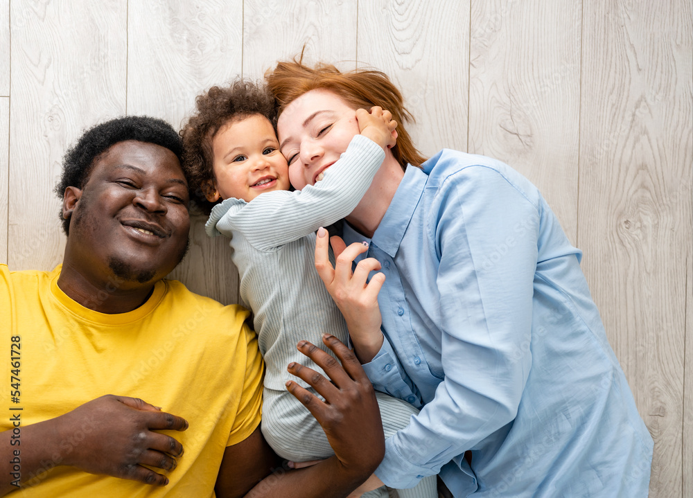 Portrait of a beautiful cheerful smiling mixed-race family. Lying on a ...