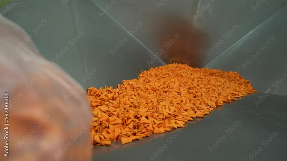 Pouring cone-shaped chips onto the production line in a food factory ...
