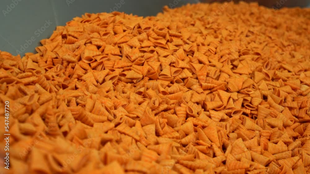 Pouring cone-shaped chips onto the production line in a food factory ...