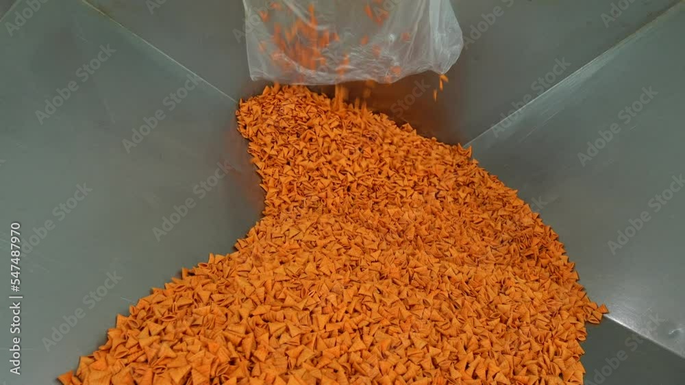 Pouring cone-shaped chips onto the production line in a food factory ...