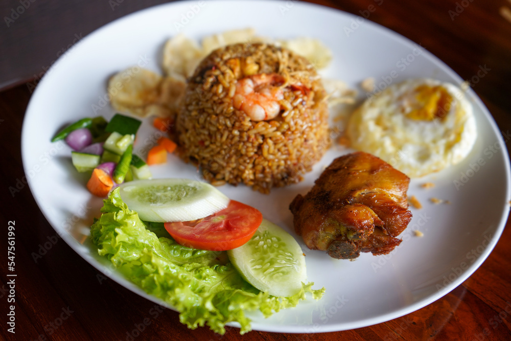 Javanese fried rice with egg and fried chicken on a white wide plate ...