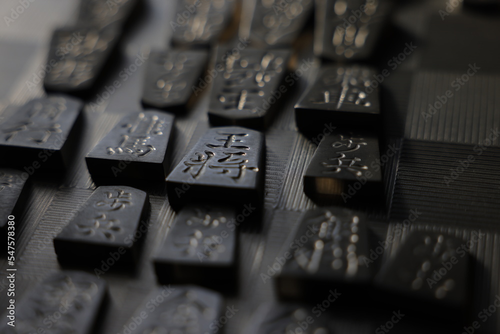 Piece of Shogi (made of titanium) on titanium plate. Shogi is the ...