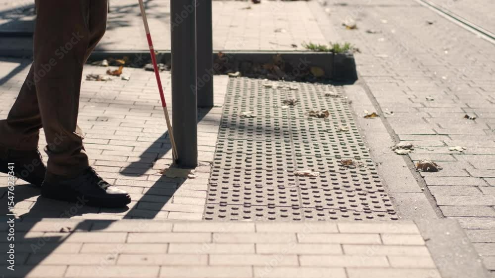 Visually impaired man is walking on a tactile warning tile with the ...