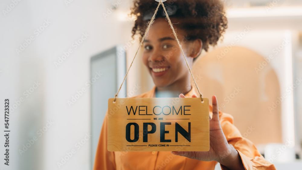Woman setting open sign board through the door glass., Owner of a small ...