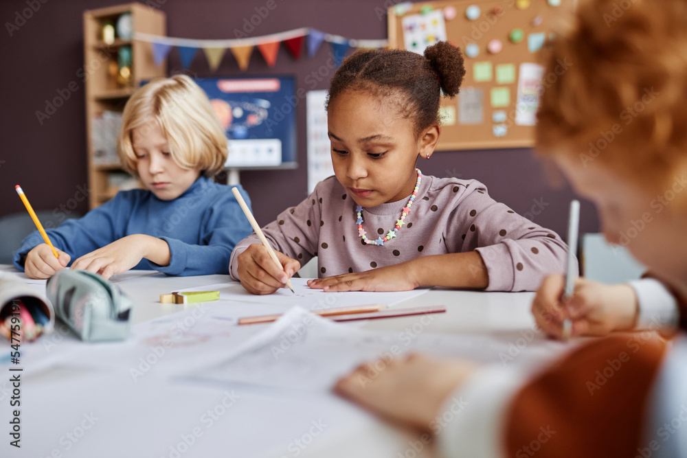 Cute African American learner of primary school drawing with crayons ...