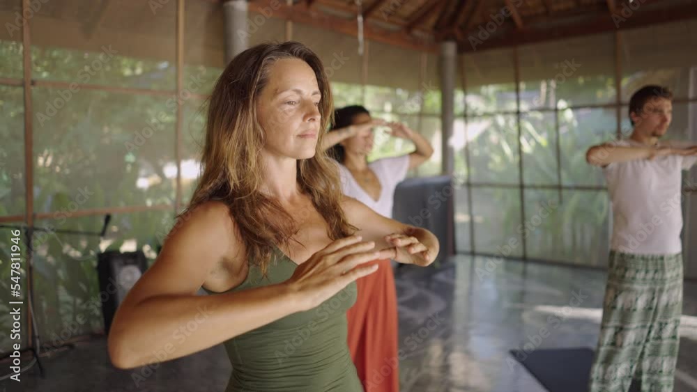 Multi-ethnic group breathe and meditate together. They raise their arms ...