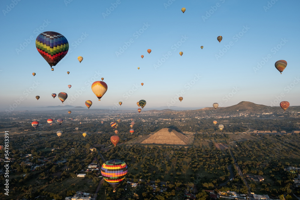 Hot air balloons float above the Pyramid of the Sun as the sun rises in ...
