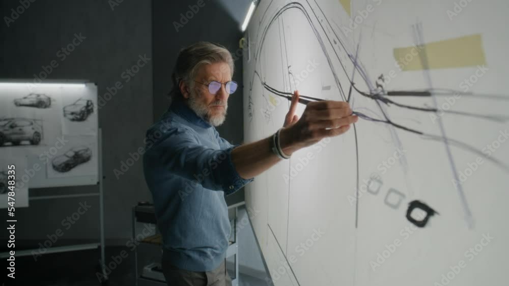 Senior automotive male designer creating sketch with duct tape on paper ...