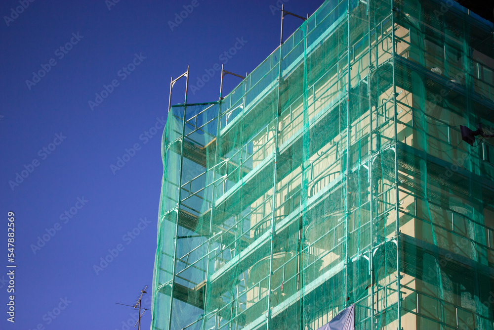 Multistory building facade covered with green protective construction ...