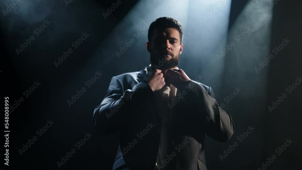 Portrait of a chic guy in a white shirt in a dark interior. A close-up ...