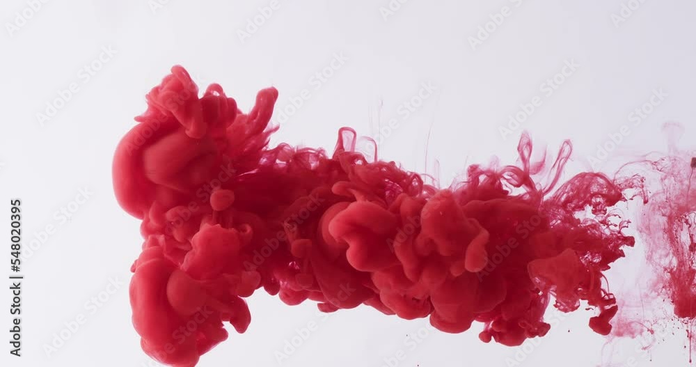 Red liquid ink spreads in transparent water and forms volumetric figure ...