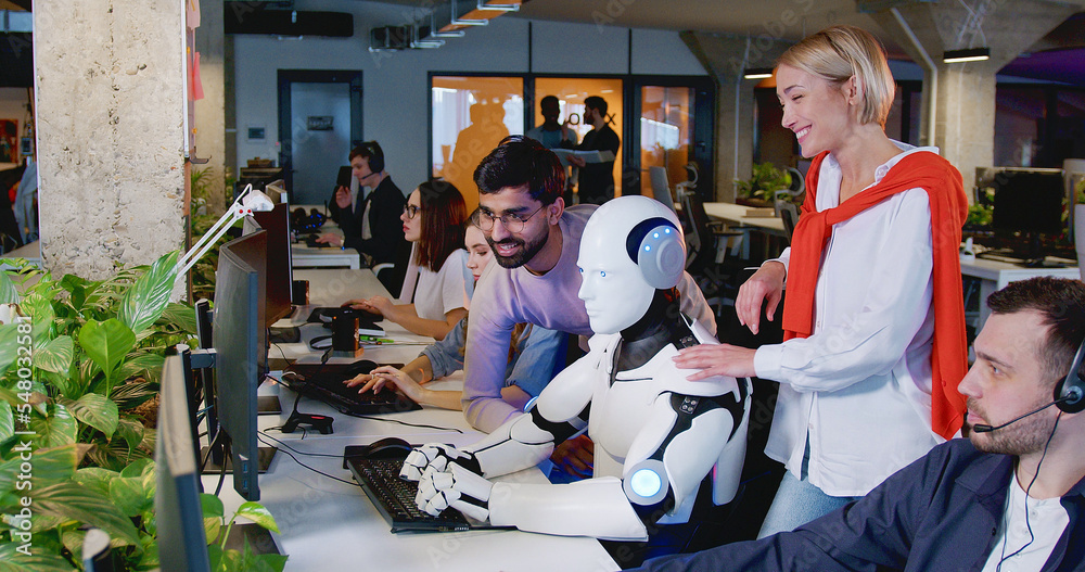 Happy multietnic people standing and looking at humanoid working in ...