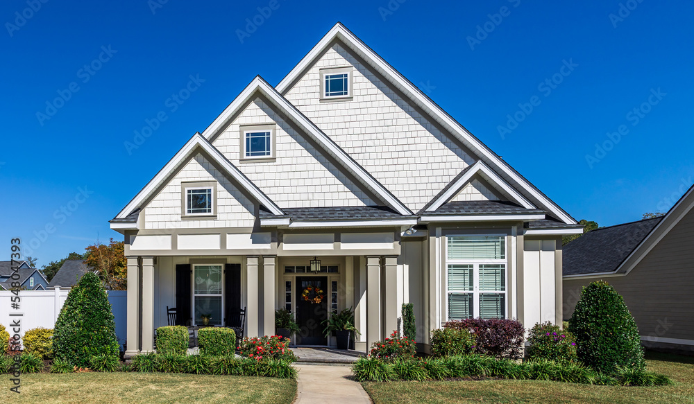 The front view of a cottage craftsman style white house with a triple ...