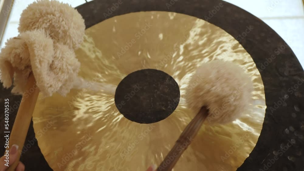 Gong and gong mallets, close up. Female hands hit the gong with soft ...