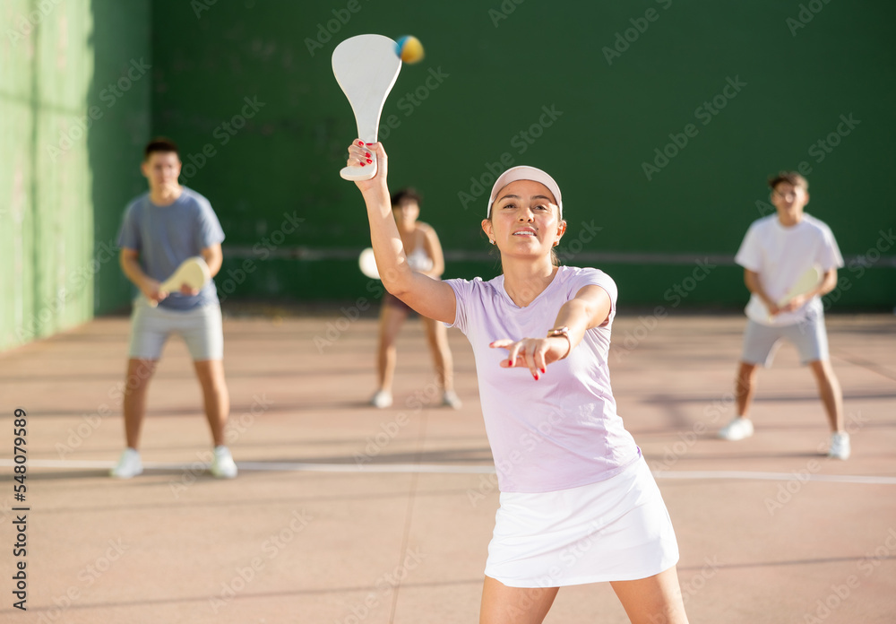 Latin woman serving ball with paleta during Basque pelota game outdoors ...
