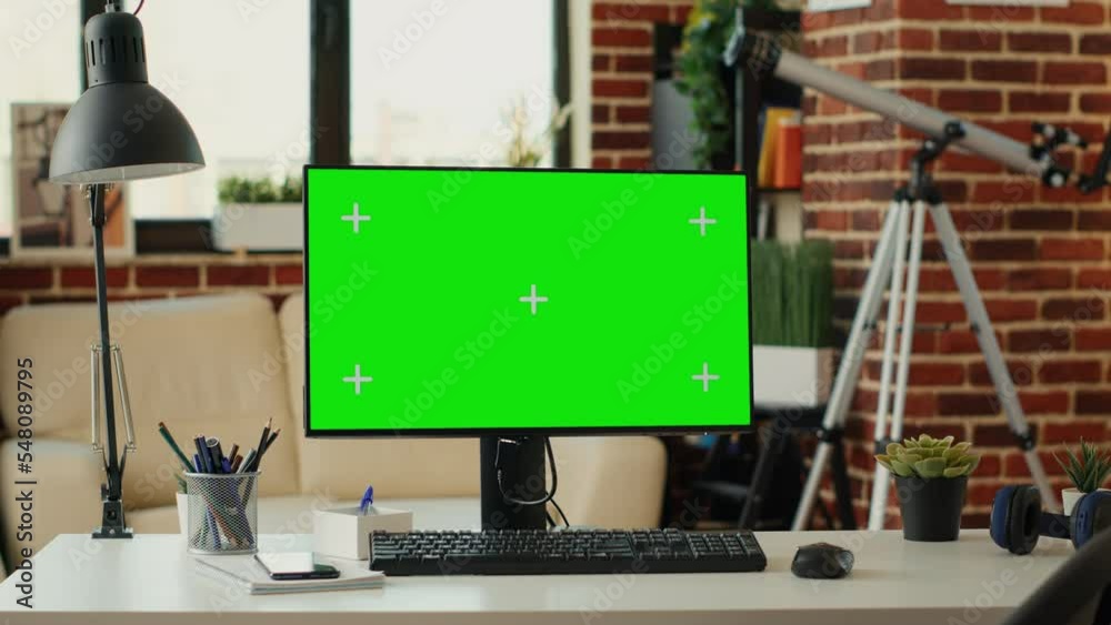 Greenscreen display on monitor with empty table in living room, workspace with chroma key blank ...