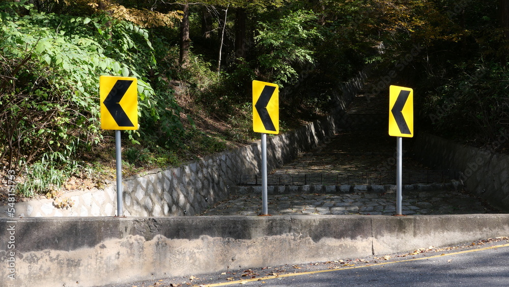 Three individual road signs each with black arrow on yellow background ...