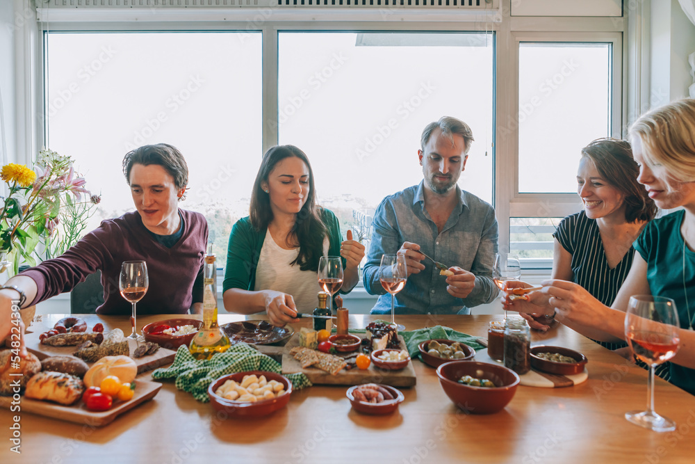 people sitting around a table full of finger food and wine - home party ...