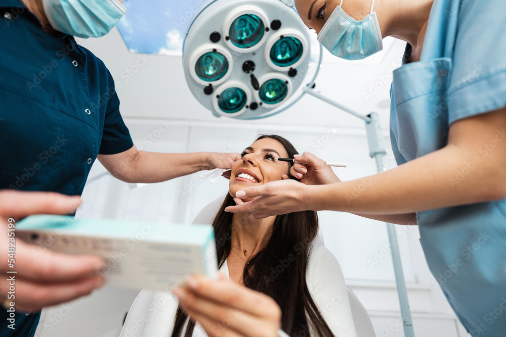 Beautiful and happy brunette woman at beauty medical clinic. She is ...