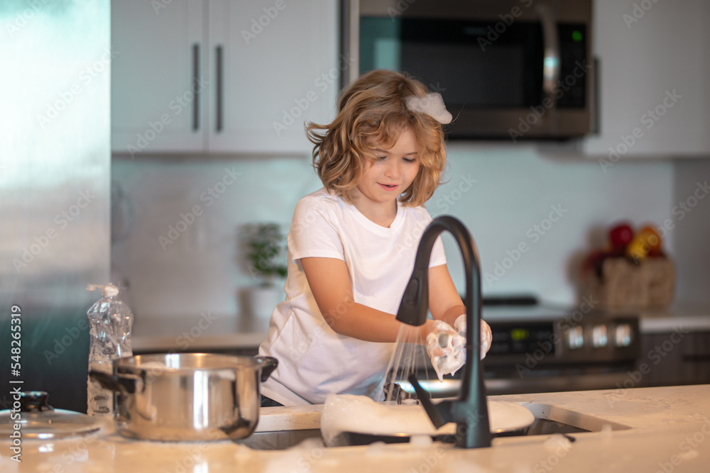 Funny twin boys helping in kitchen with washing dishes. Children having ...