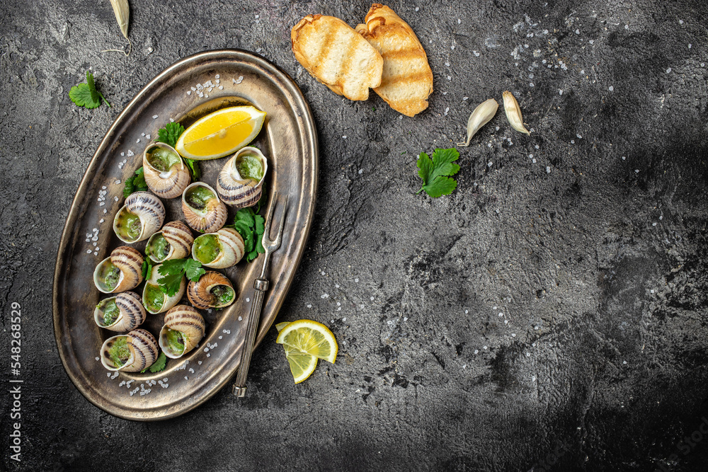 Delicious cooked sea escargo snails with herbs, butter, garlic on metal ...