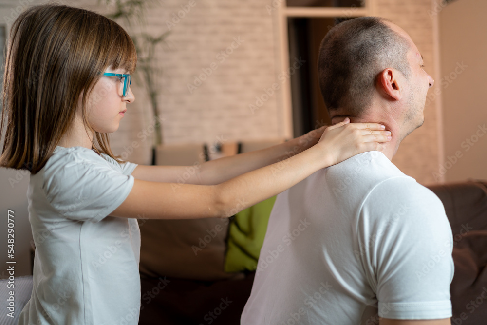 Side view of daughter massaging father's neck during evening at living ...