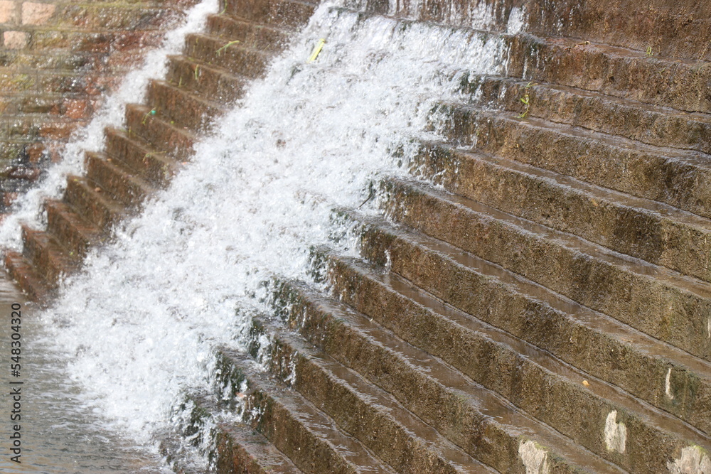 Water is flowing on steps that is built on a small overflow dam used to ...