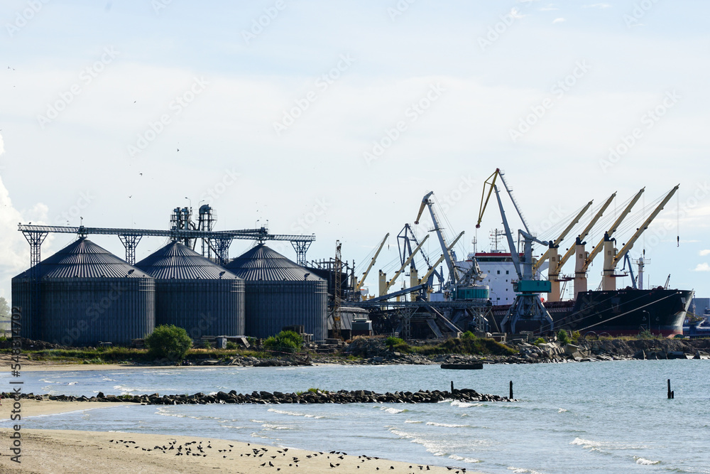 Harbor view with grain terminal silos, many shore cranes and bulk ship ...