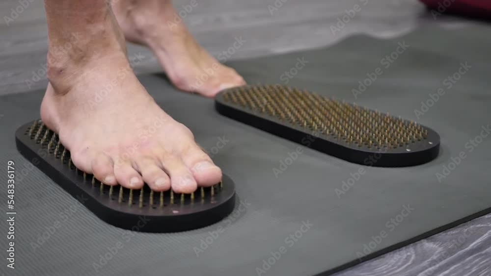 A man with bare feet steps on Sadhu's boards with sharp nails to gain ...
