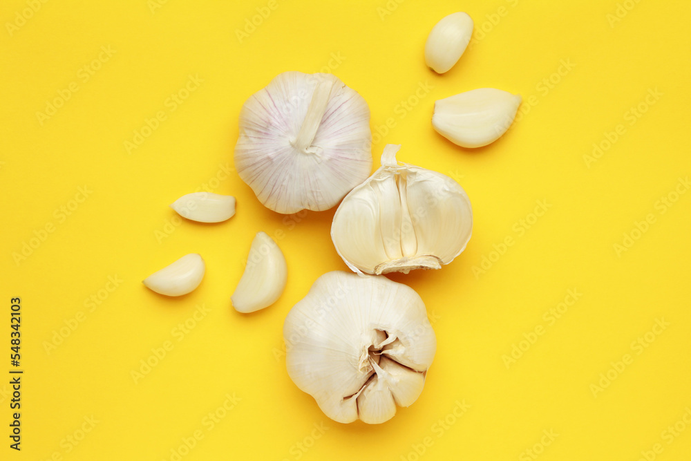 Fresh white unpeeled head bulb of garlic and garlic cloves on yellow ...