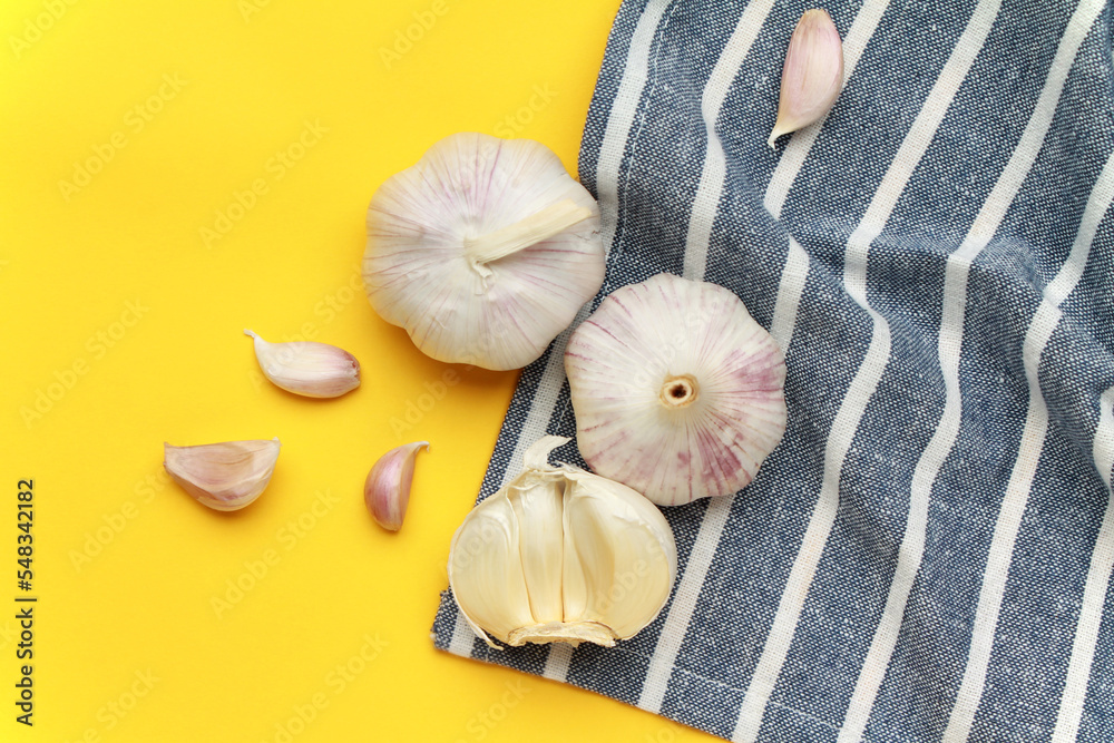 Fresh white unpeeled head bulb of garlic and garlic cloves on yellow ...