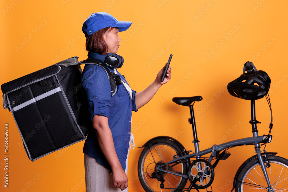 Slide view of takeaway delivery worker standing beside bike while ...