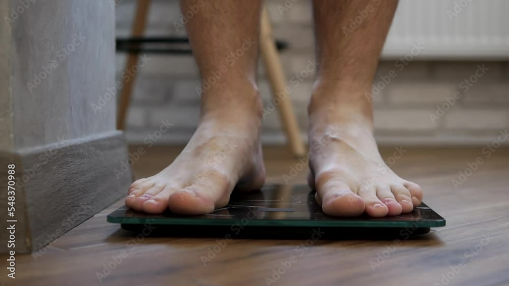 Bare feet of a man stand on a floor scale. A person is weighed on a ...