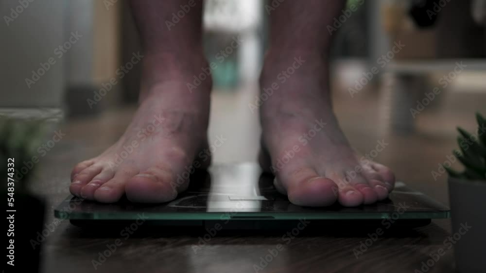 Barefoot men's feet stand on floor scales. A person is weighed on a ...