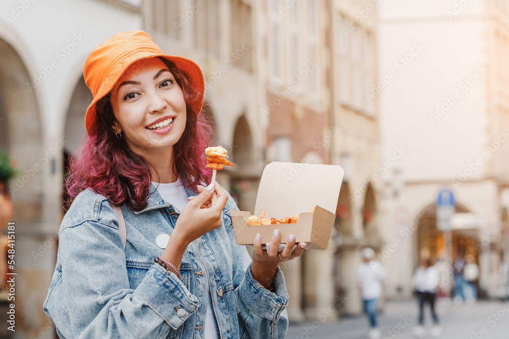 Cheerful happy girl snacking on fast food with shrimp in batter or ...