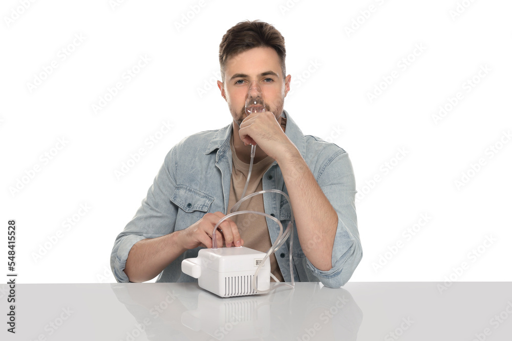 Sick man using nebulizer for inhalation at table on white background ...