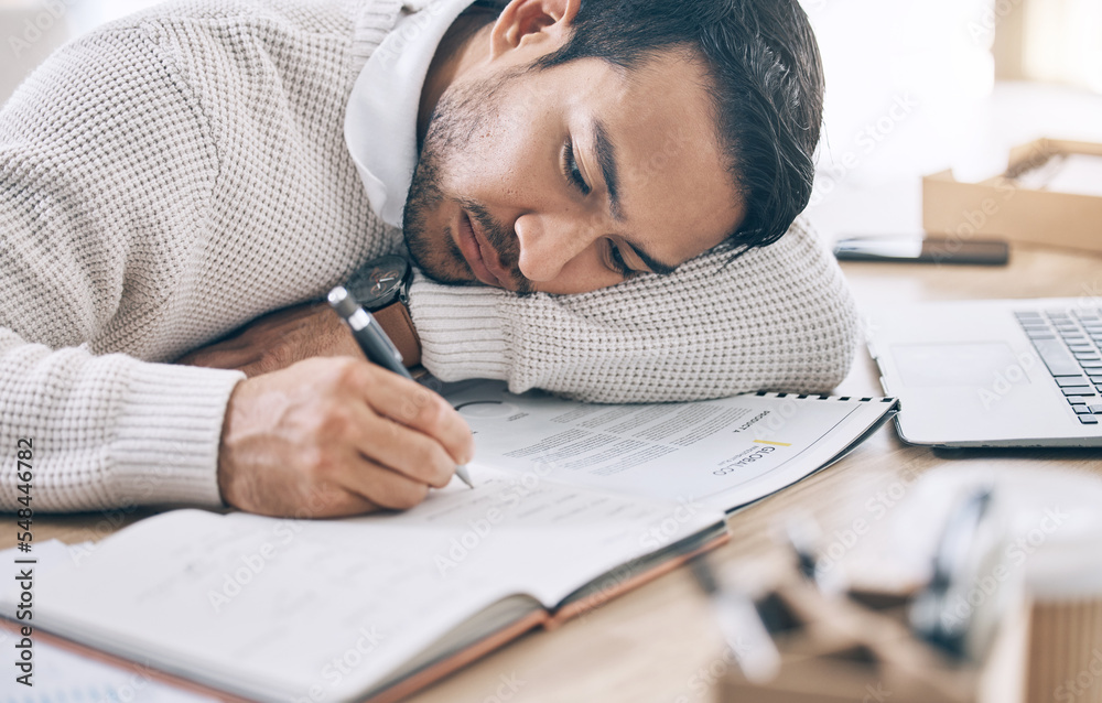 Bored, writing and diary with a business man lying on his desk at work ...