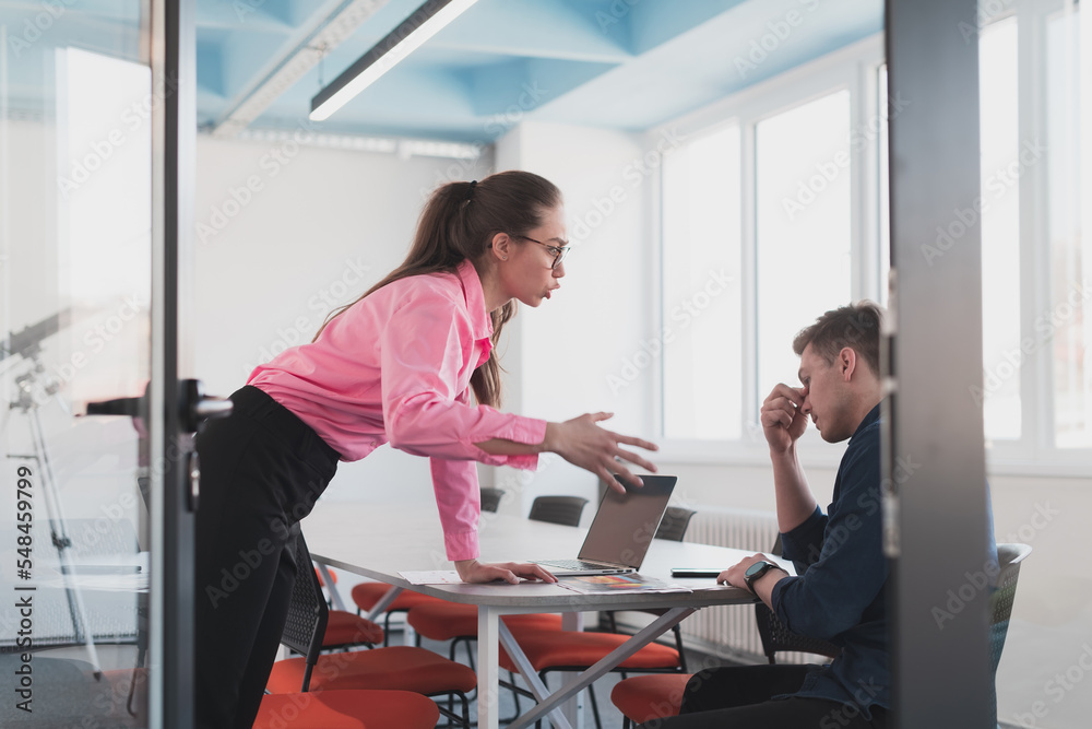 Emotional couple of young colleagues arguing in modern office. Business ...